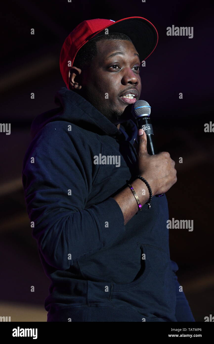 Comedian Michael Che is shown performing on stage during a "live" stand ...