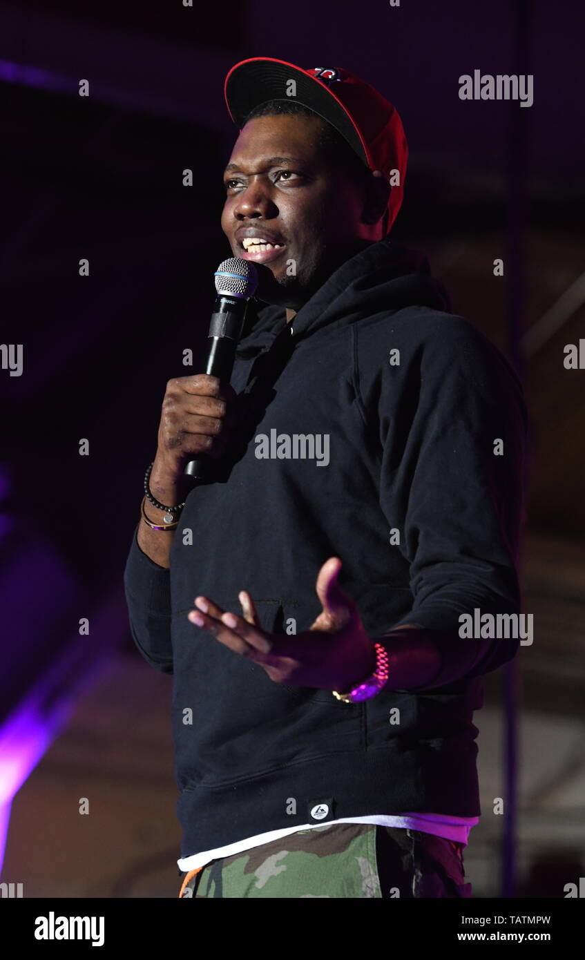 Comedian Michael Che is shown performing on stage during a "live" stand ...