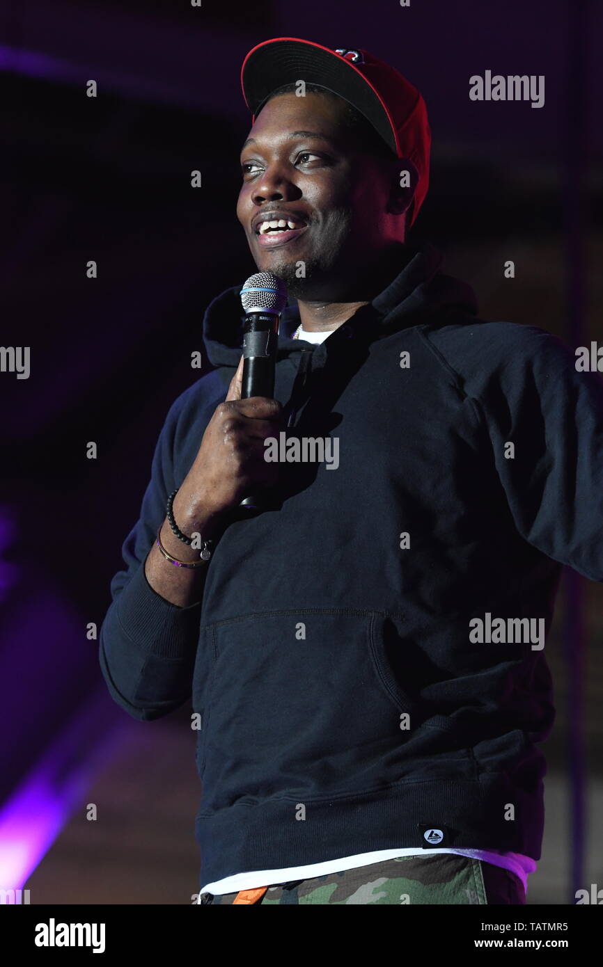 Comedian Michael Che is shown performing on stage during a "live" stand ...