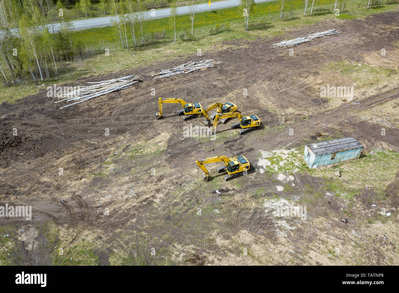 Aerial side view of four yellow crawler excavators standing on ground ...