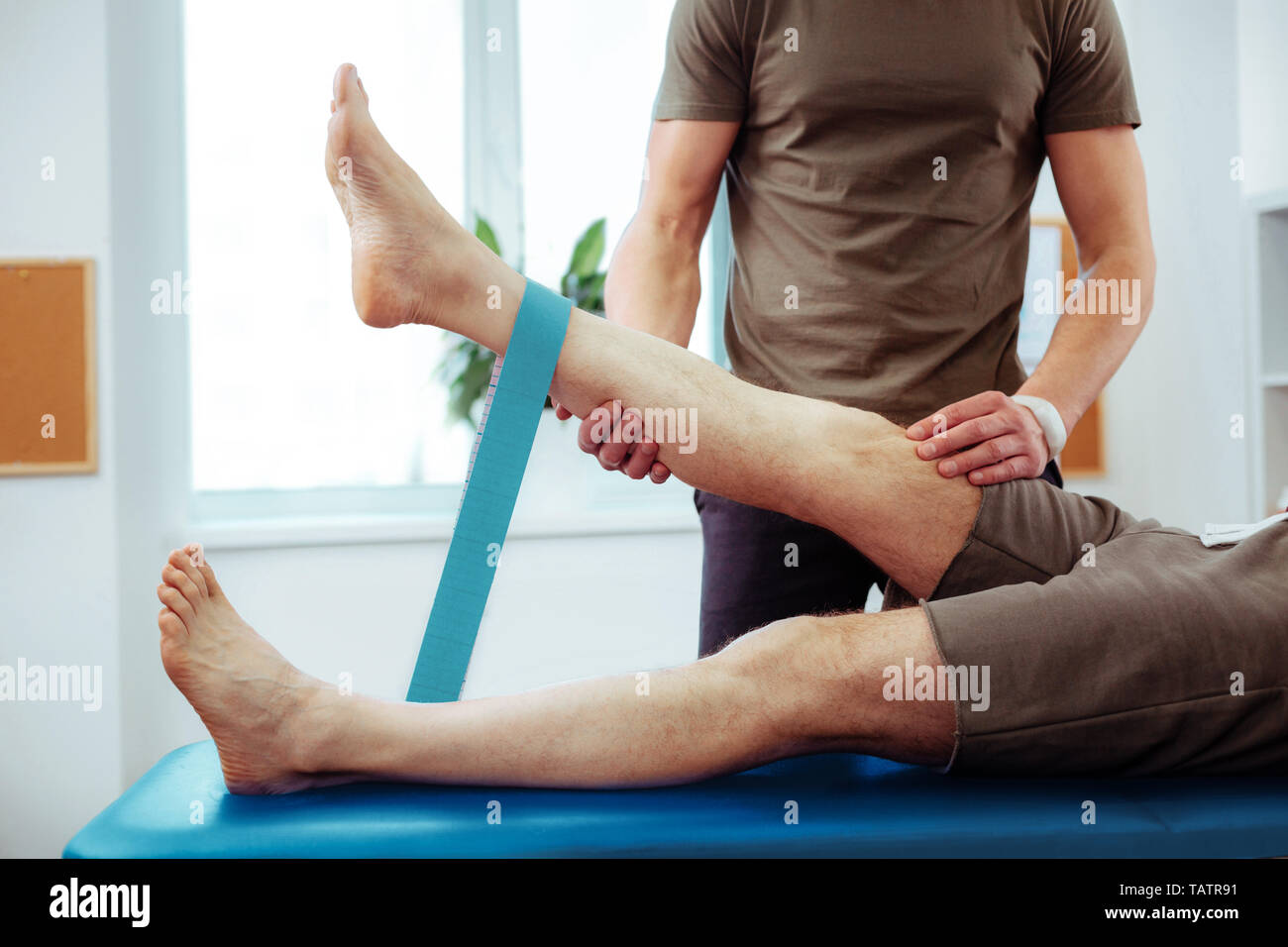 Elastic band exercises. Close up of a male leg being raised while doing ...