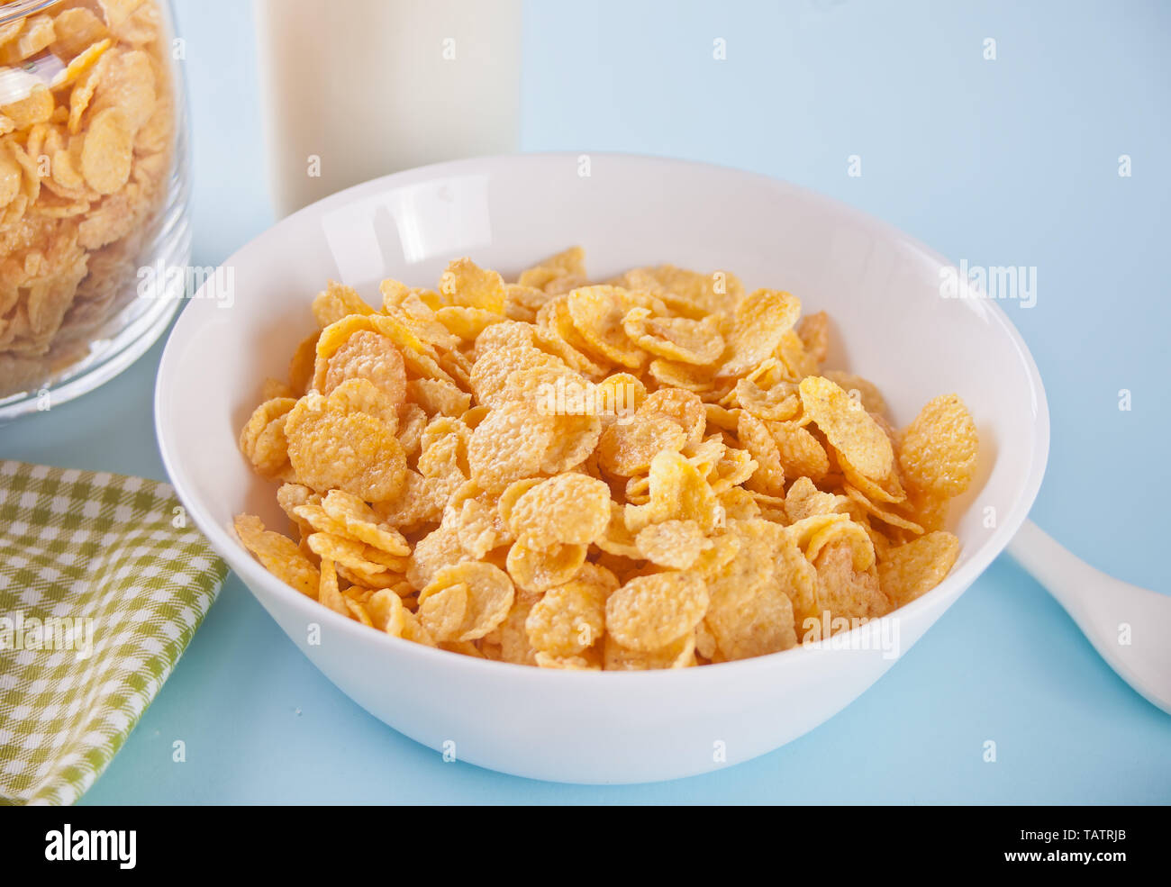 A bowl of dry corn flakes cereal on the blue table for health breakfast ...