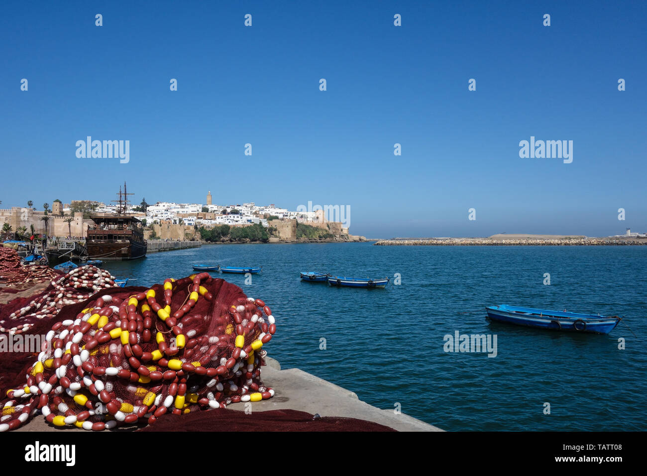 Bay with parked boats. Marina promenade with some piles of fishing nets ...