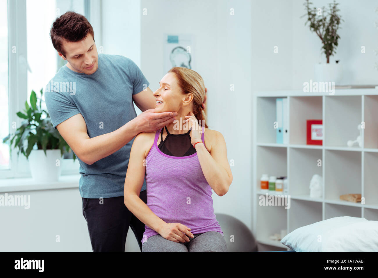 Professional masseur. Pleasant strong man standing behind his patient ...