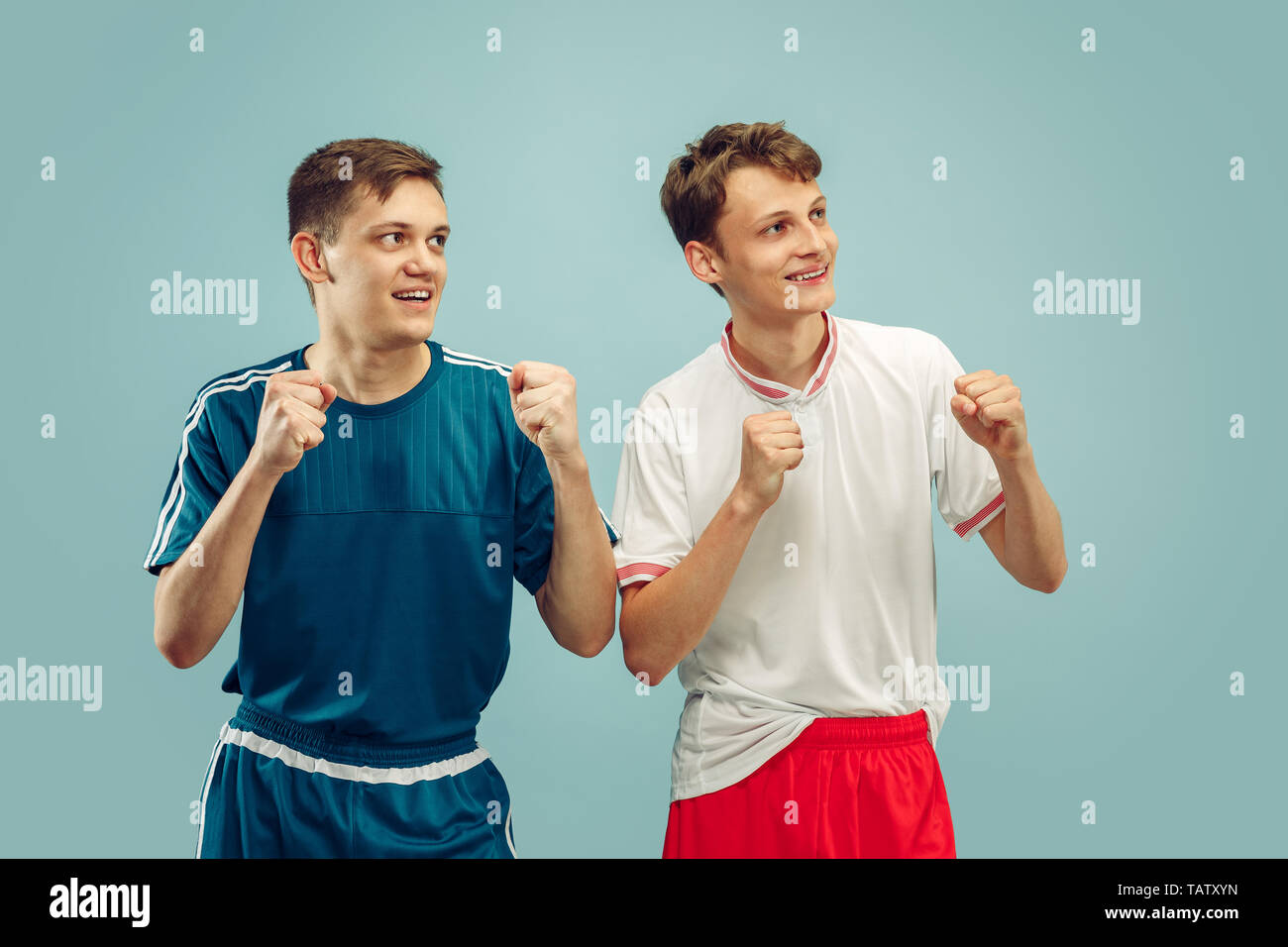 Two young men standing in sportwear isolated on blue studio background ...