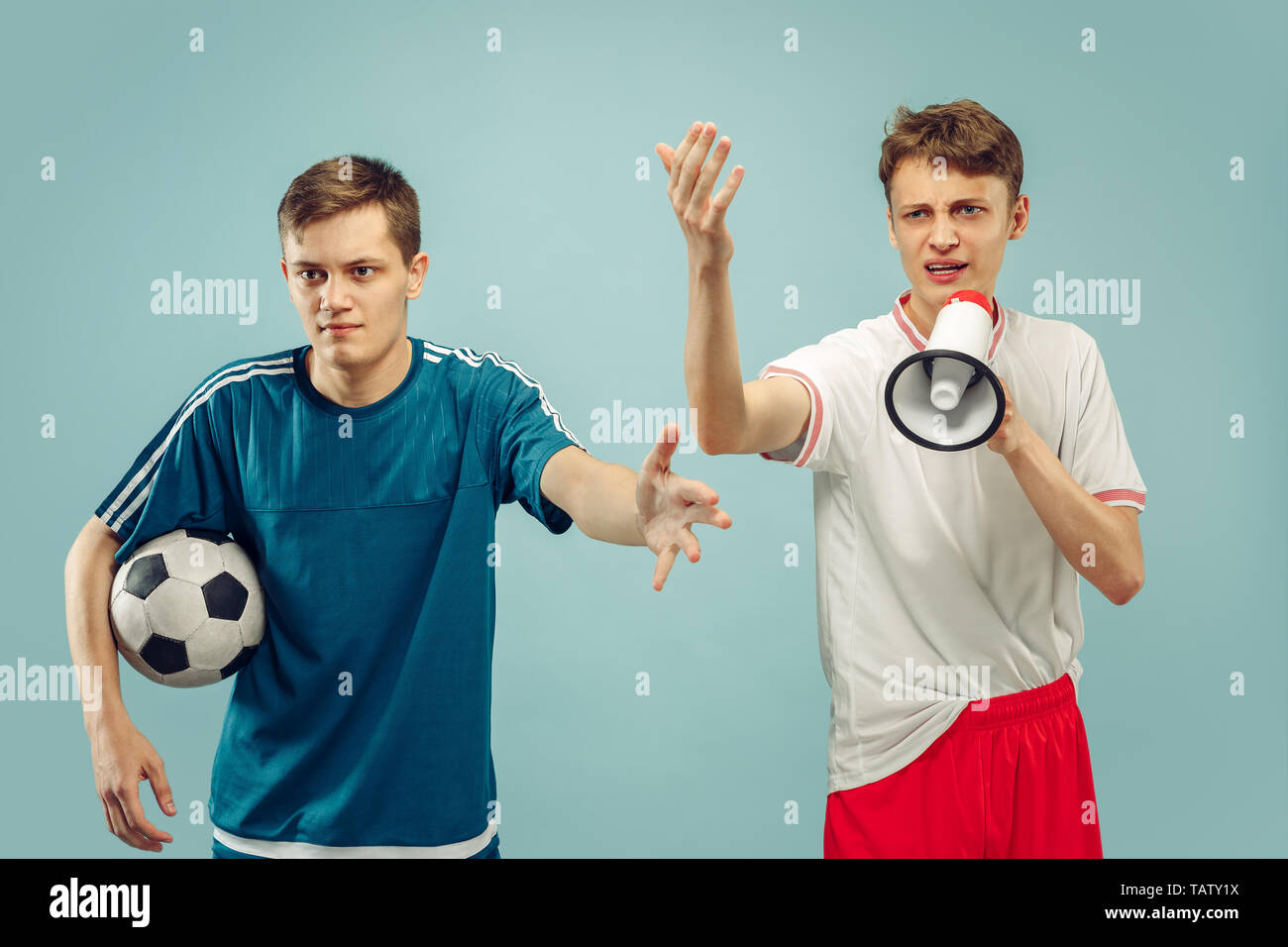 Two young men standing in sportwear isolated on blue studio background ...