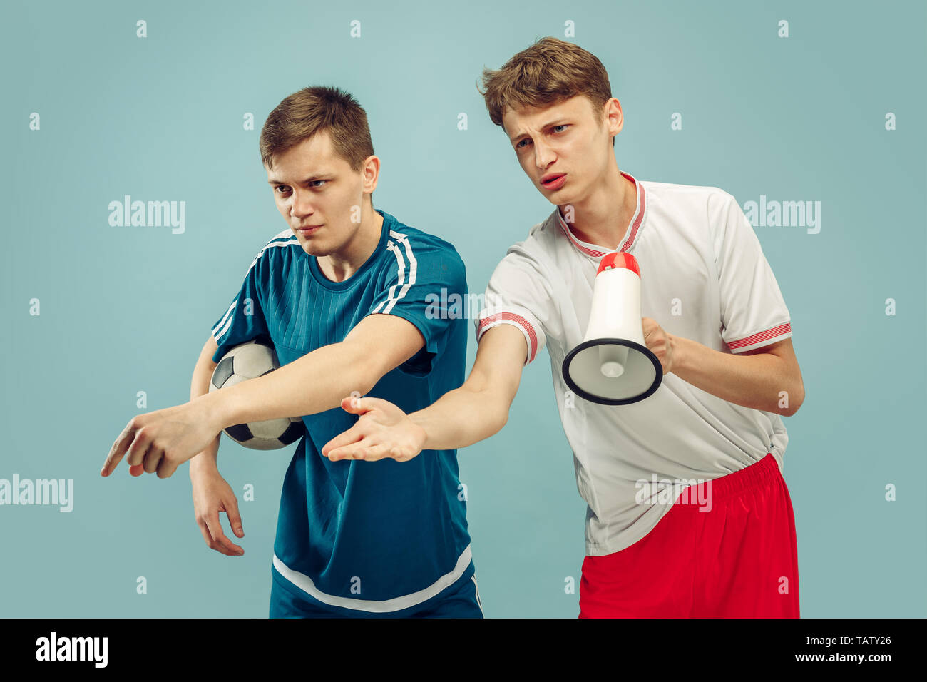 Two young men standing in sportwear isolated on blue studio background ...