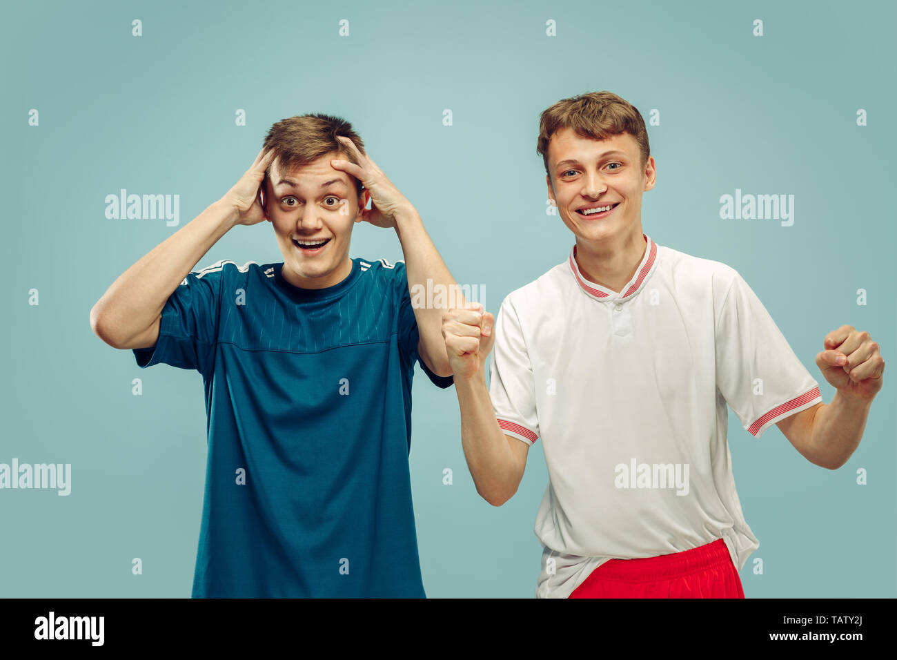 Two young men standing in sportwear isolated on blue studio background ...