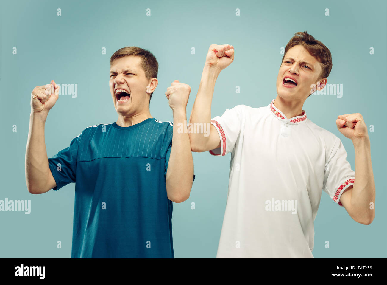 Two young men standing in sportwear isolated on blue studio background ...