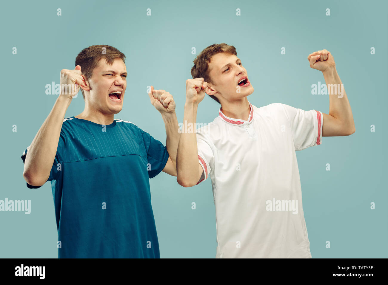 Two young men standing in sportwear isolated on blue studio background ...