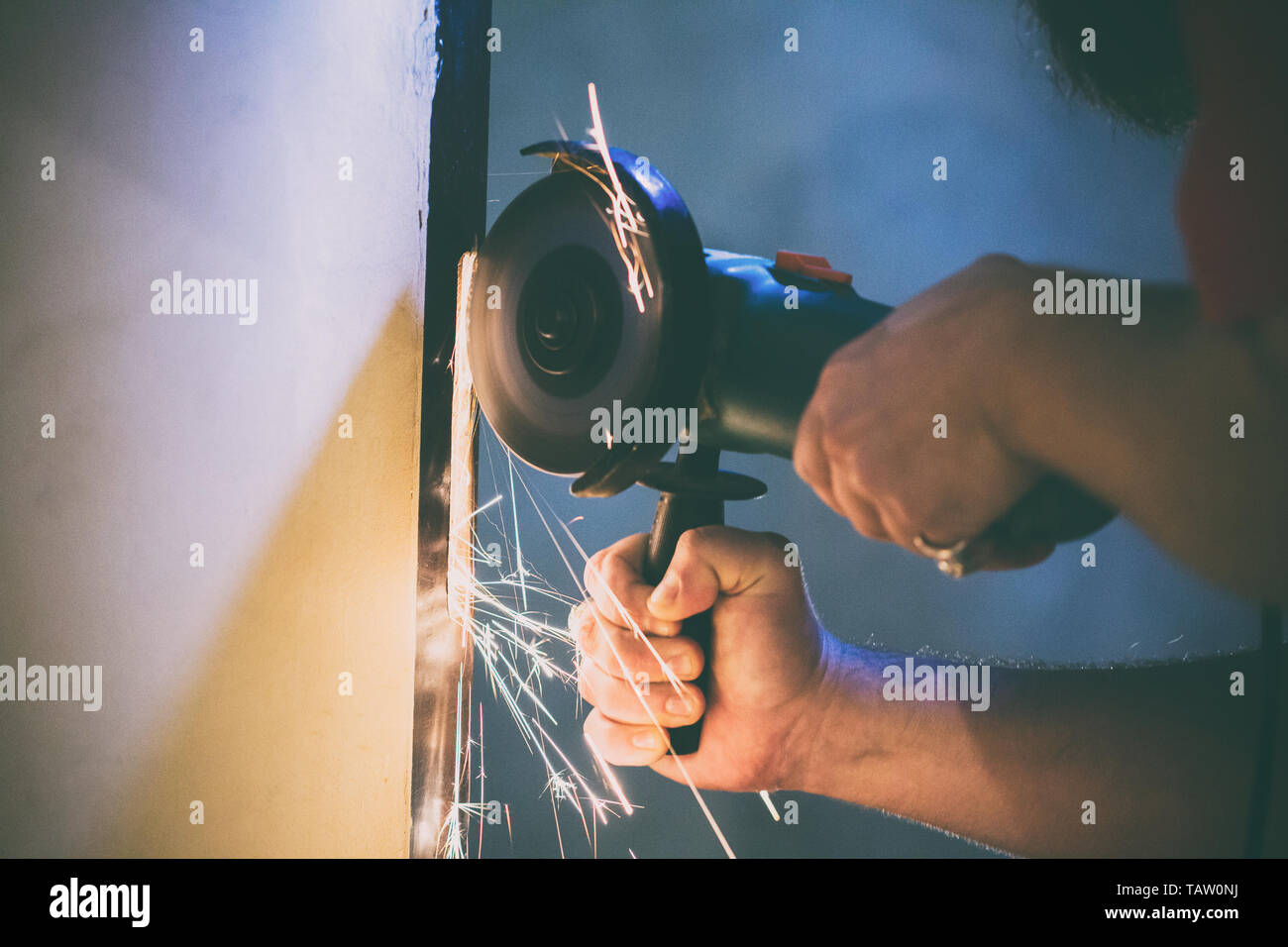 A man repairs a metal door in the basement of his house using a manual ...