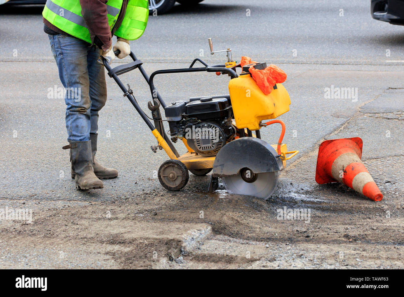 An employee of the road maintenance service removes old asphalt with a ...