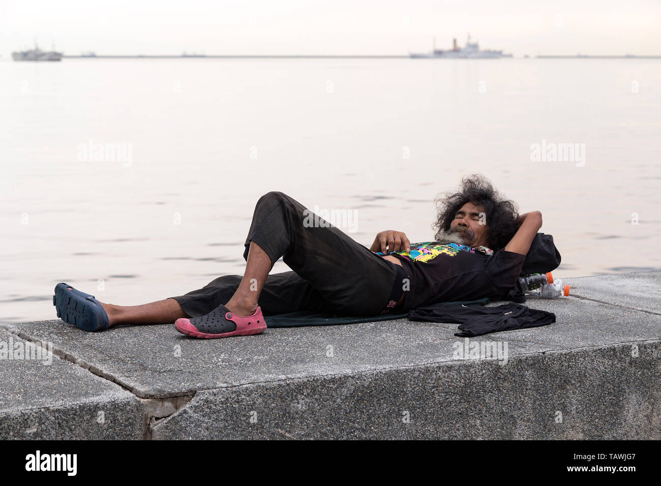 Manila, Philippines - June 22, 2016: Homeless man sleeping by the sea ...