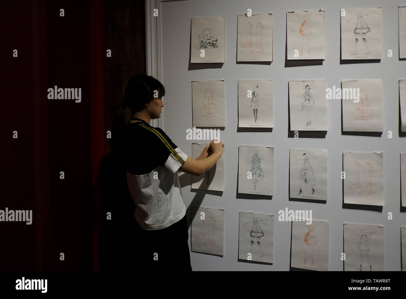 Young woman hanging sketch drawings by SHIATZY CHEN fashion house which ...