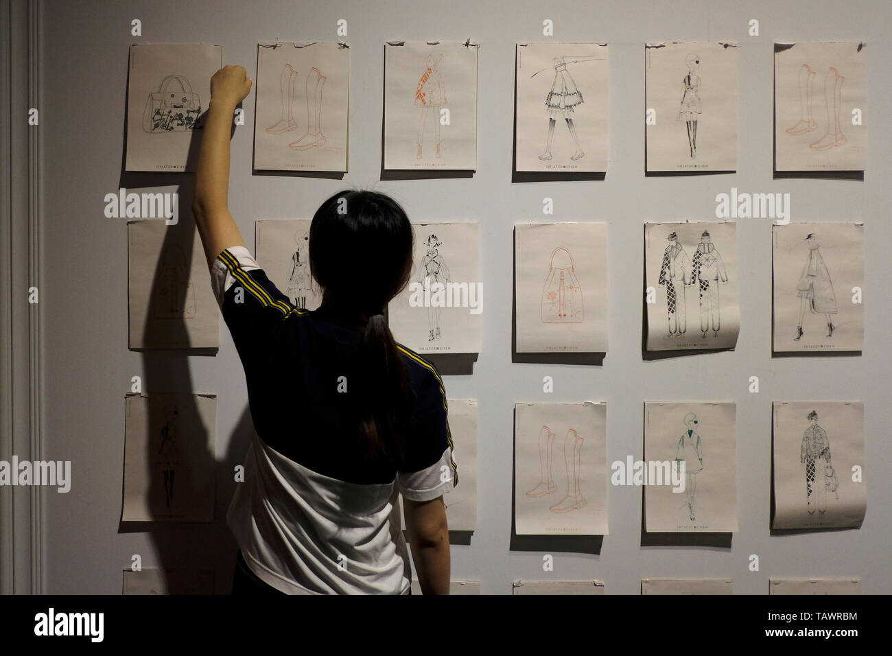 Young woman hanging sketch drawings by SHIATZY CHEN fashion house which ...