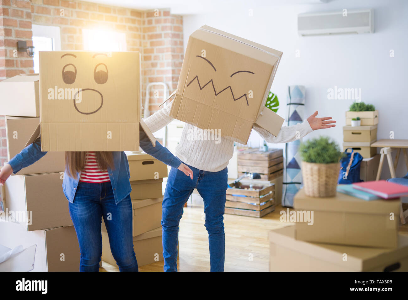 Crazy couple wearing boxes with funny faces over head, having fun happy ...