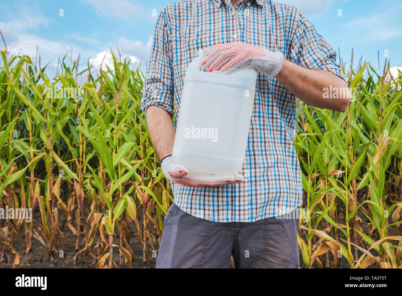 Farmer holding unlabeled pesticide jug in field, agronomist recommends ...