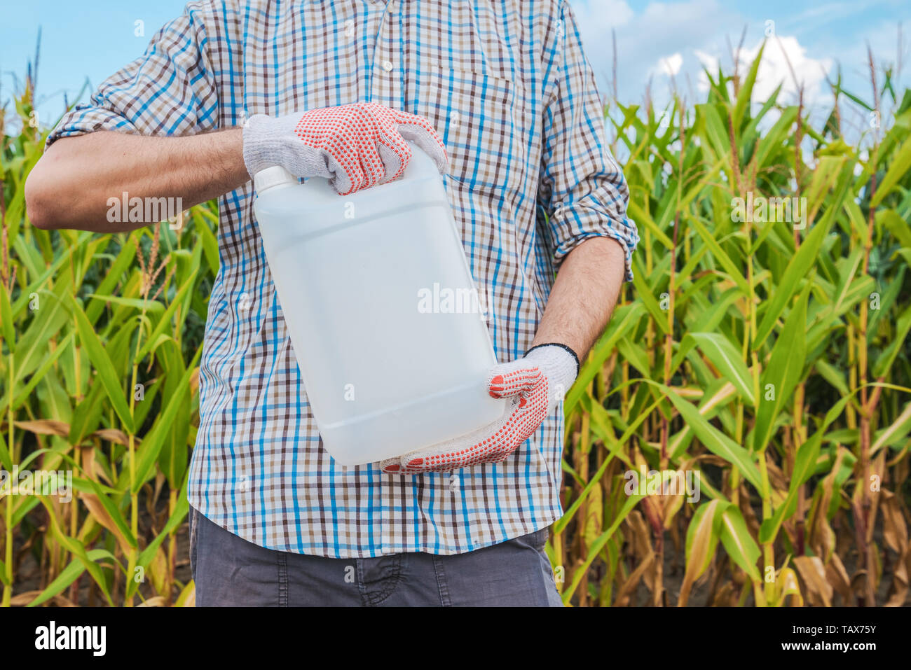 Farmer holding unlabeled pesticide jug in field, agronomist recommends ...