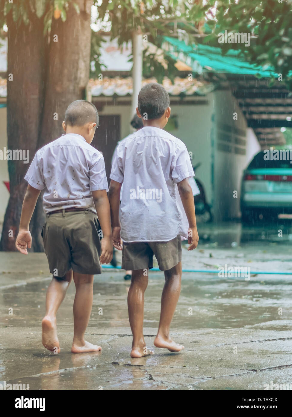 Boy students leave the classroom to walk on the street after heavy rain ...