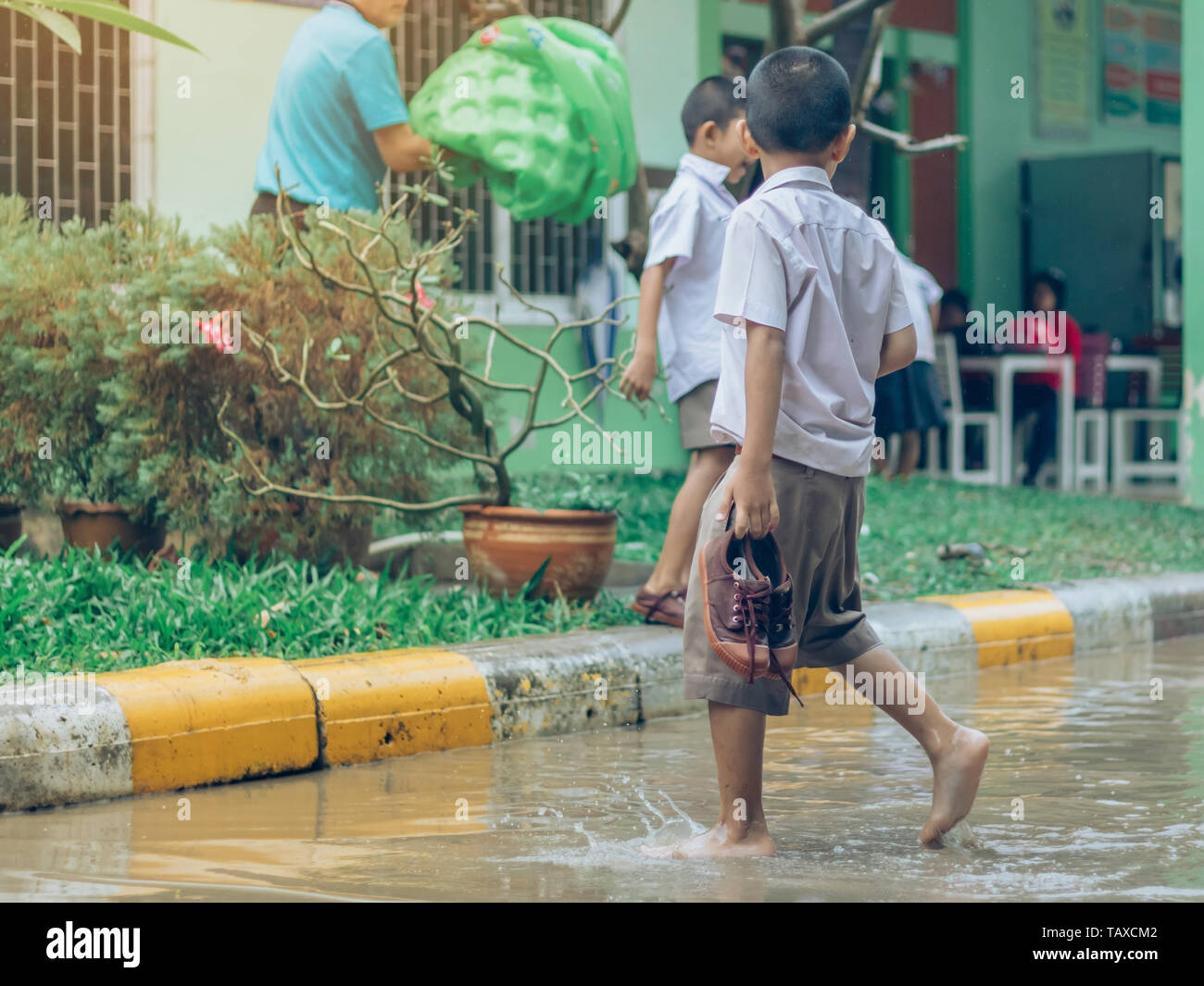 Boy students leave the classroom to walk on the street after heavy rain ...