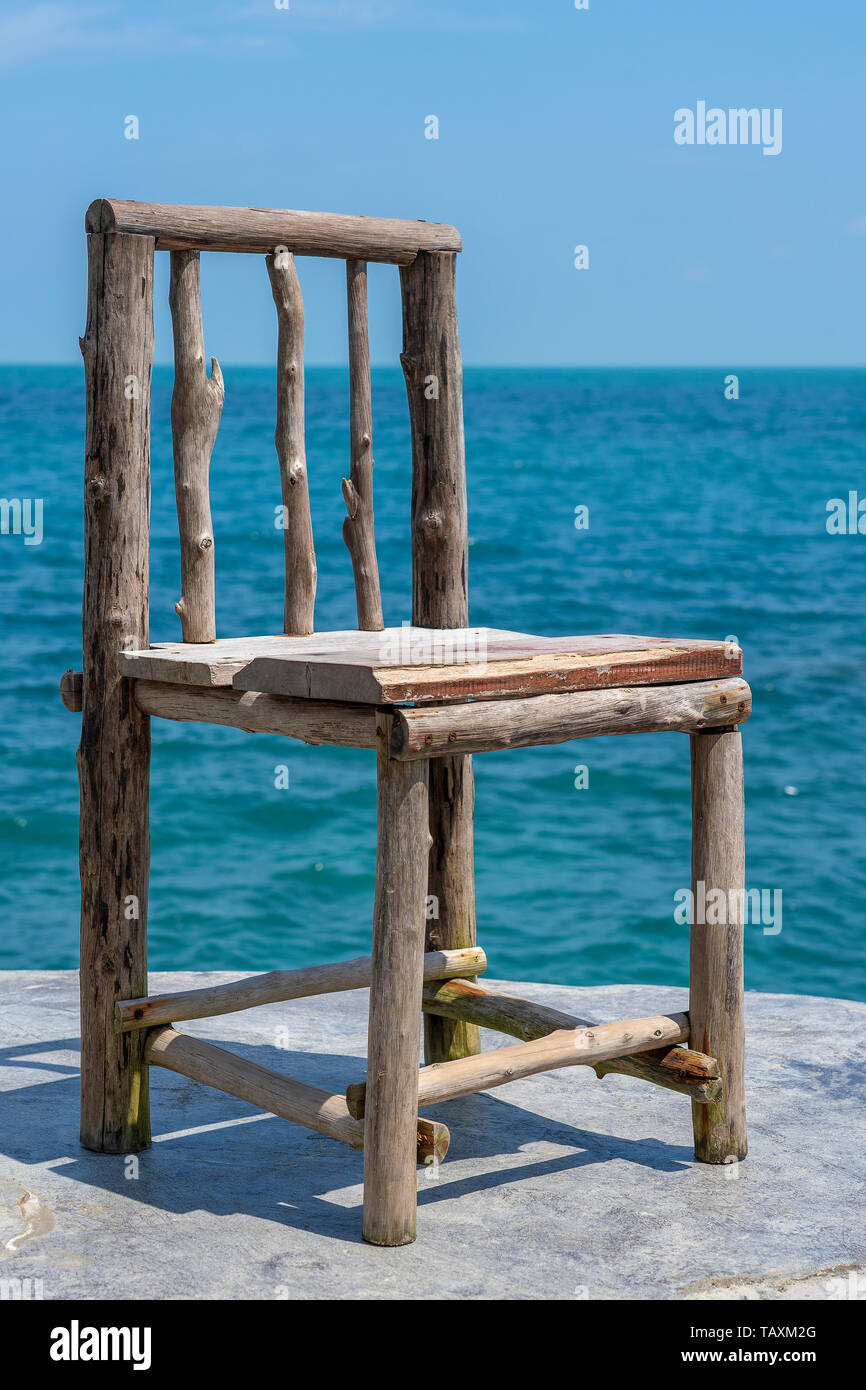 Wooden chair in empty cafe next to sea water in tropical beach. Close up. Island Koh Phangan ...