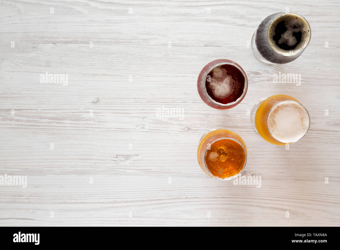 Different beers on a white wooden background, top view. Overhead, from ...