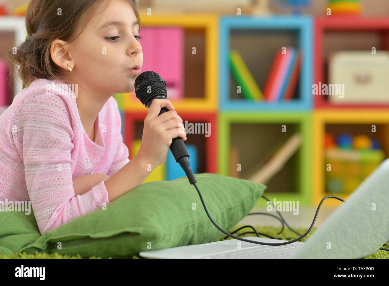 Portrait of girl singing karaoke with laptop while lying on floor Stock ...