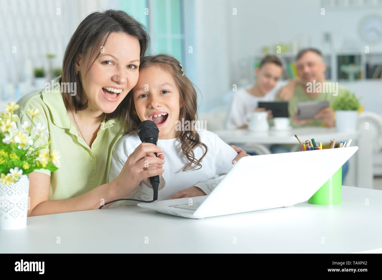 Cute little girl and her mother singing karaoke Stock Photo - Alamy