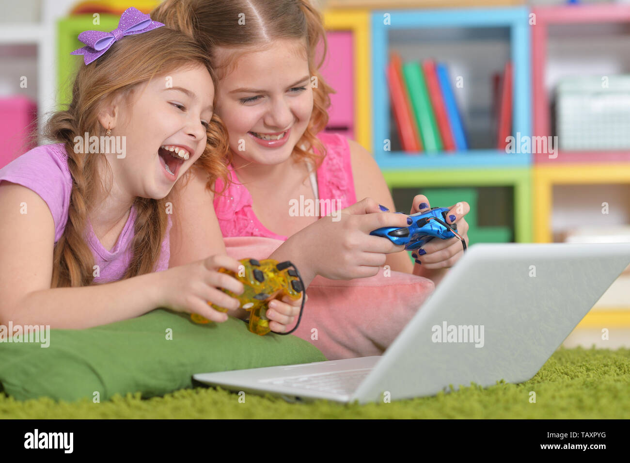 Portrait of girls playing computer game with laptop together Stock ...