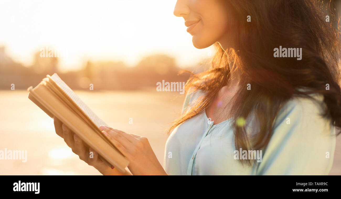 Student girl reading book outdoors, enjoying sunset Stock Photo - Alamy