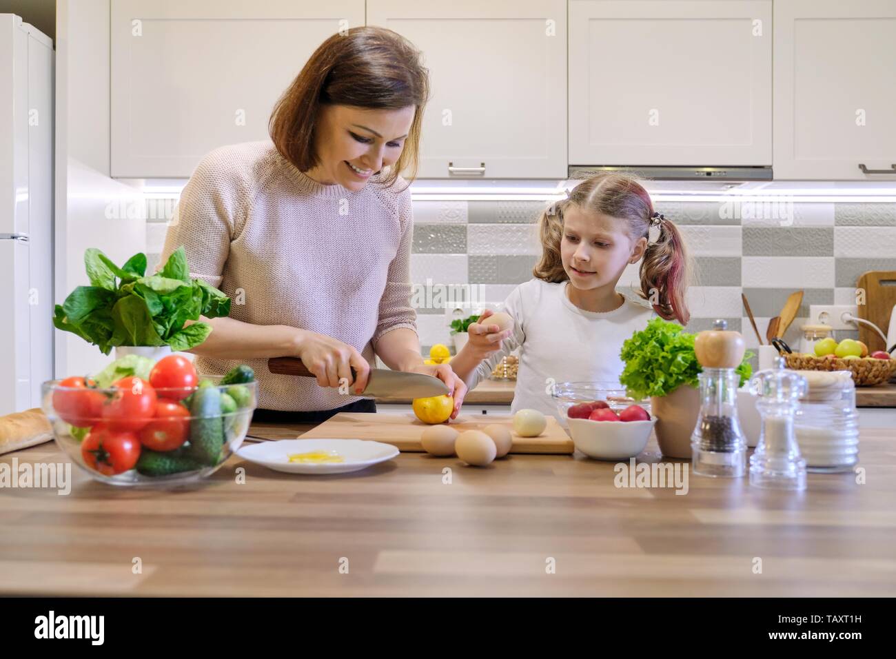 Mother and child cooking together at home in kitchen. Healthy eating ...