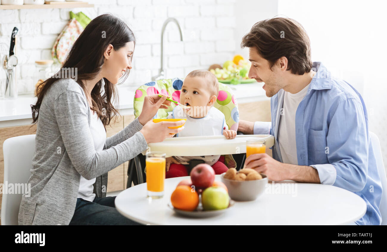 Good looking young family eating breakfast together with their baby ...