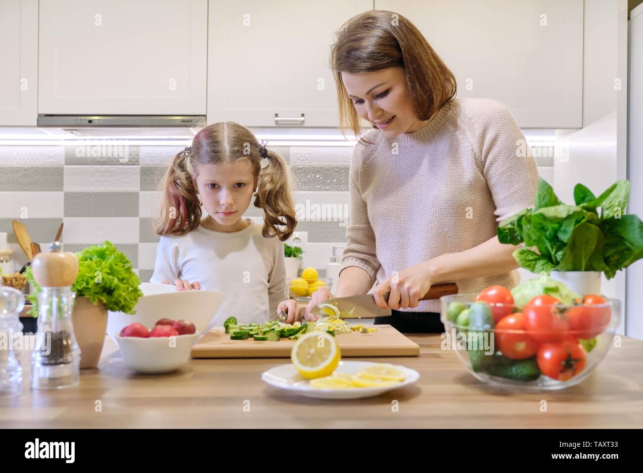 Mother and child cooking together at home in kitchen. Healthy eating ...