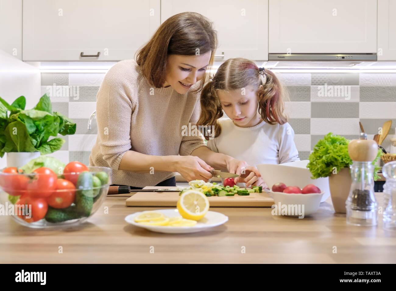 Mother and child cooking together at home in kitchen. Healthy eating ...