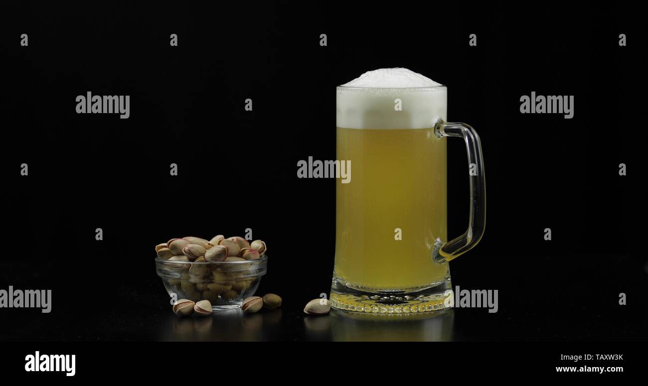 Cold Light Beer in a glass. Craft Beer close-up. Bowl of pistachios ...