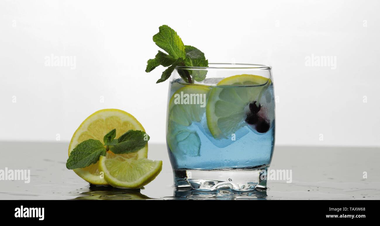 Glass with cold blue drink with leaves of mint, lime, lemon, black ...