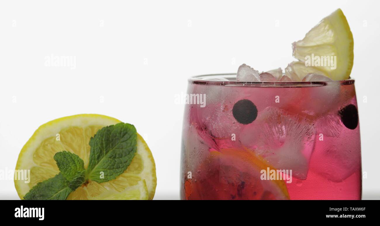 Glass with cold red drink with lemon, black currants and ice cubes ...