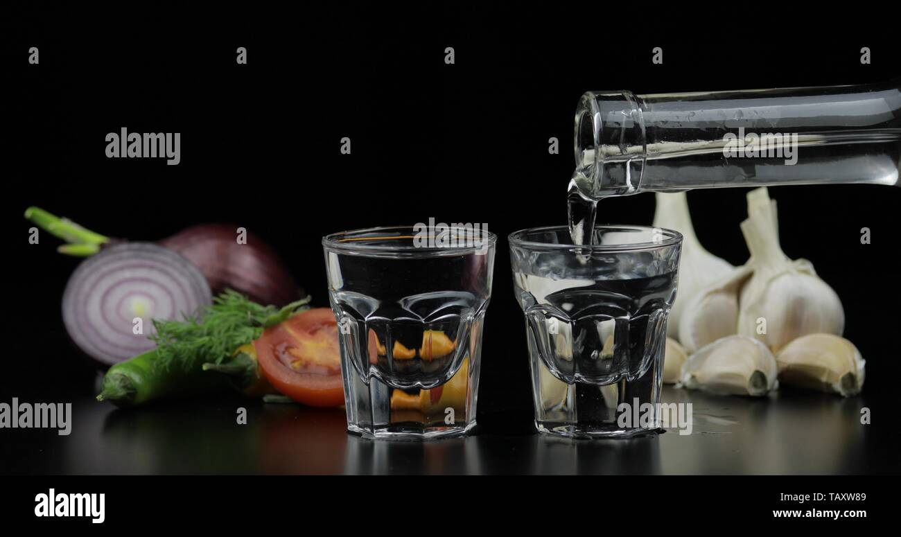 Pouring up shot of vodka from a bottle into glasses with onion, hot ...