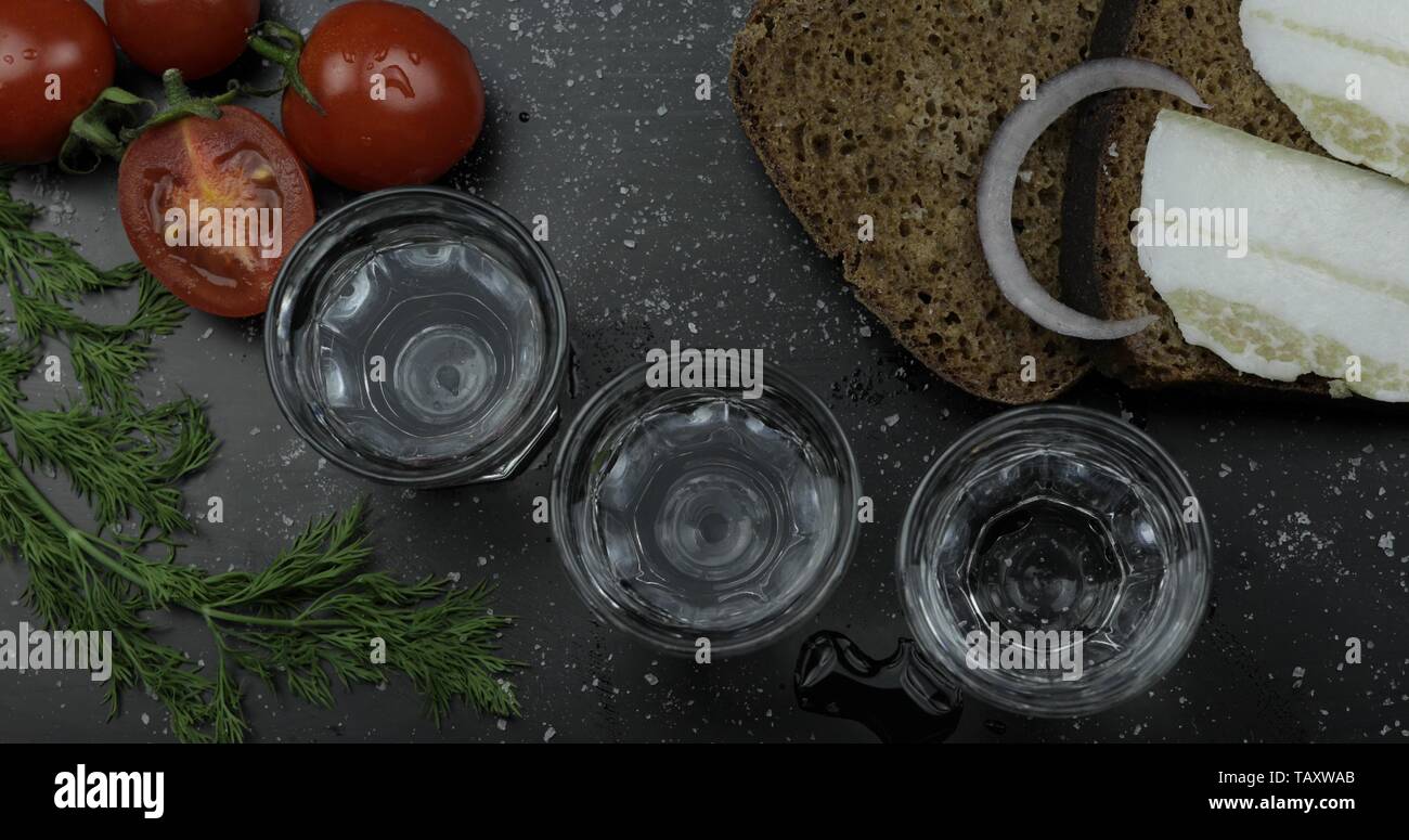 Shots of vodka in glasses. Bread with lard, onion, dill and cherry ...