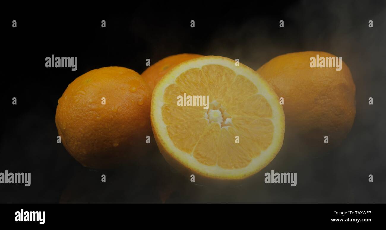 Tropical fruit orange in cold ice clouds of fog smoke on black ...