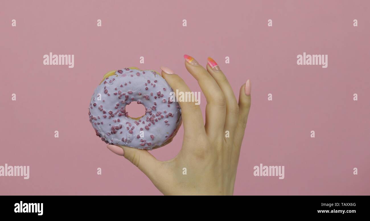 Womens hand holding blue, delicious, tasty and fresh donut on pink ...