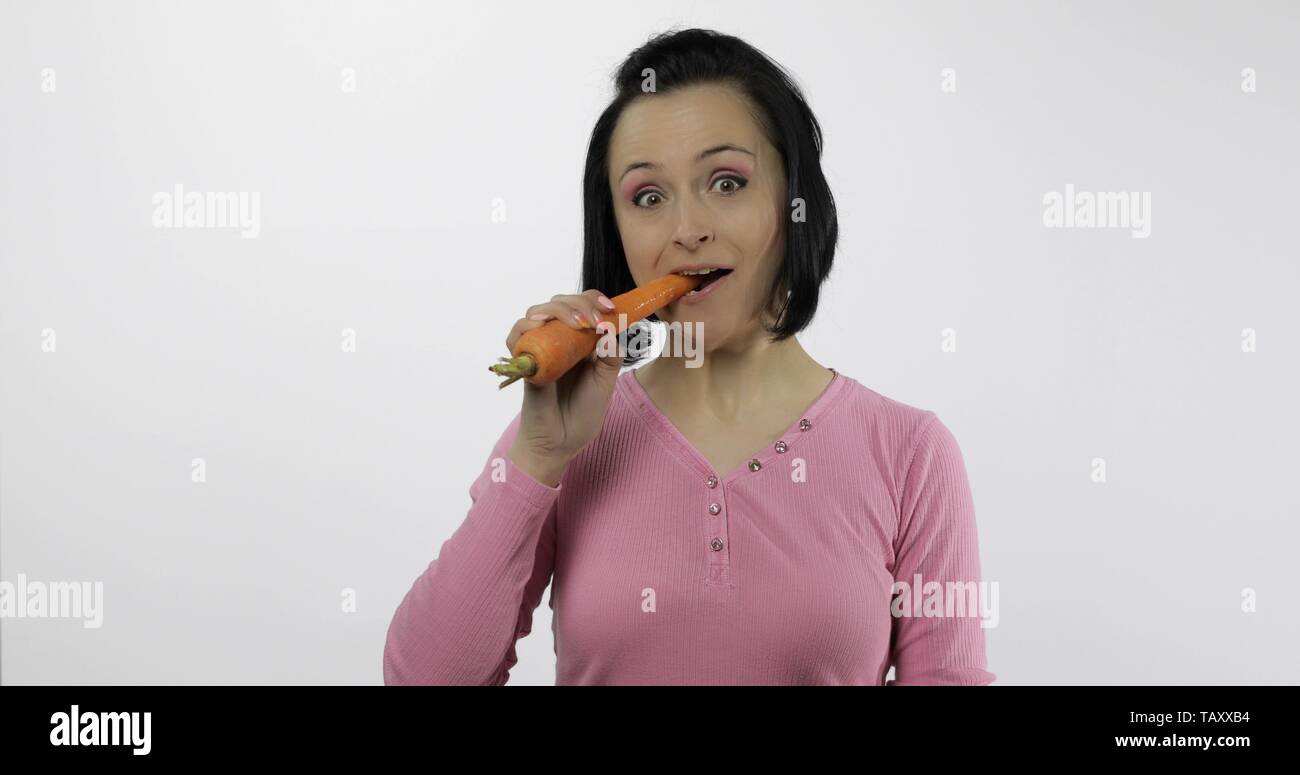 Young beautiful woman eating big carrot. Healthy nutrition. Model ...