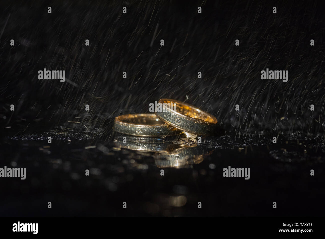 Wedding rings lying on dark surface shining with light close up macro ...