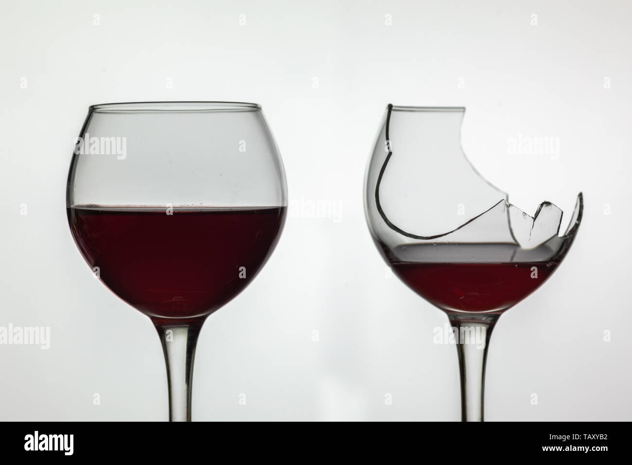 Broken and not broken wine glass with red wine on white background ...