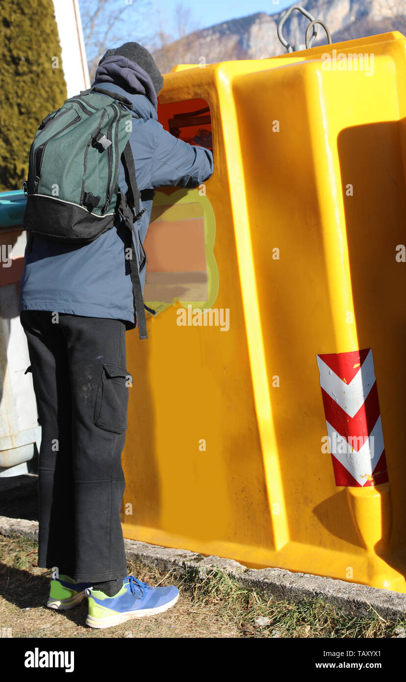 poor boy with a backpack searching in the yellow rubbish bin for ...