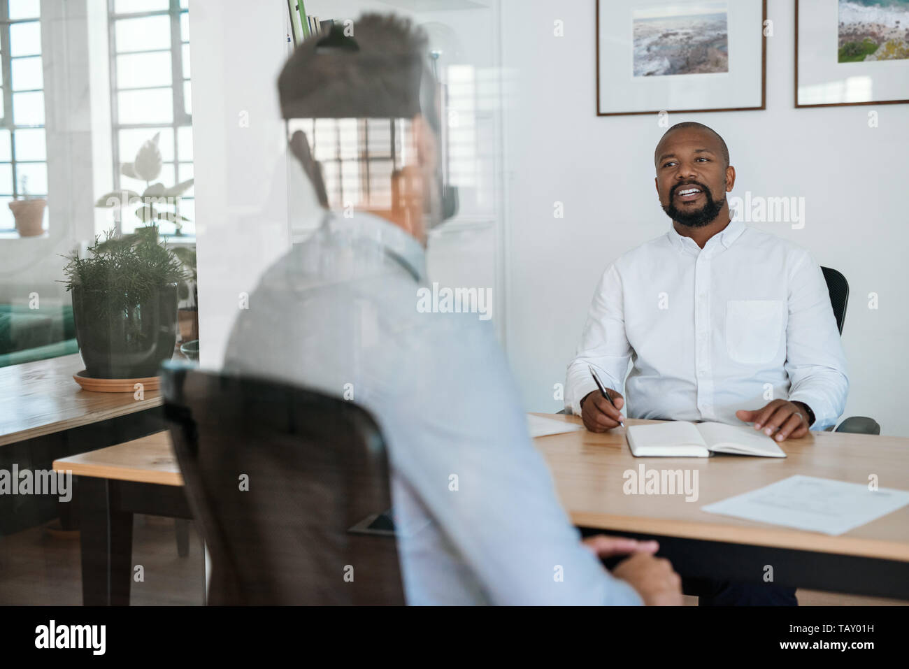 Smiling African American office manager conducting an interview with a ...