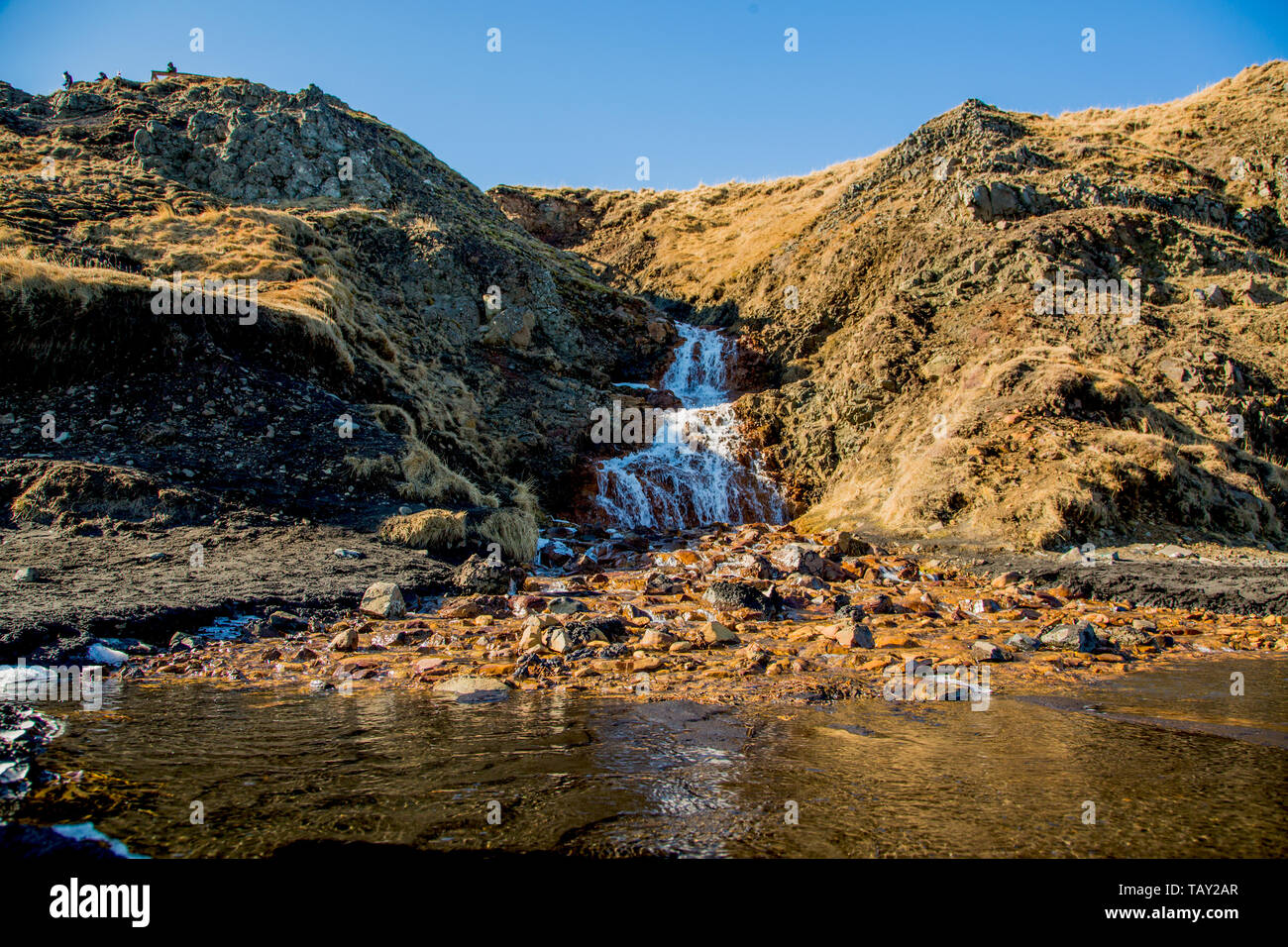 Orange waterfall from below, framed by rock, in iceland Stock Photo - Alamy