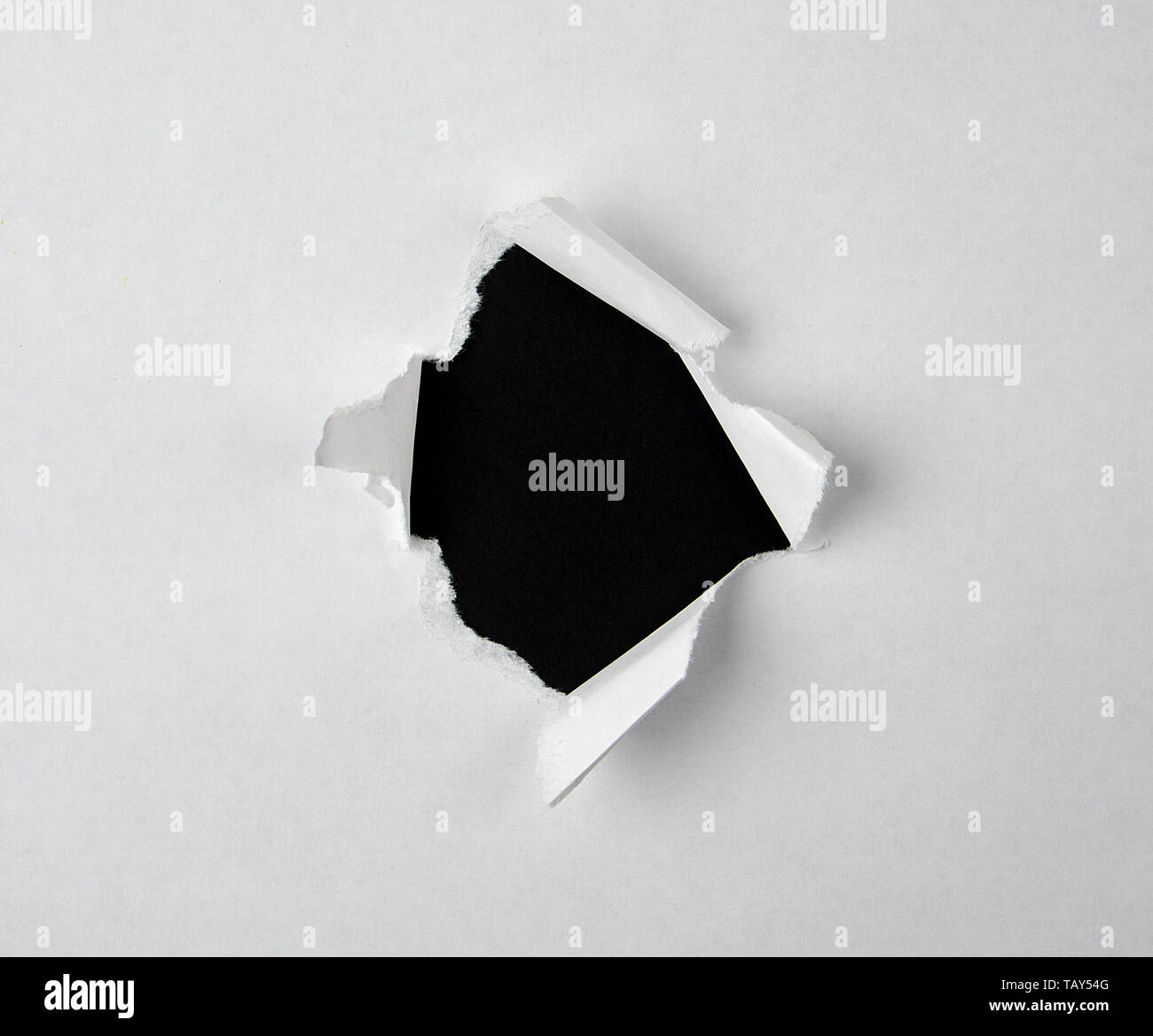 round torn hole with twisted edges in white paper, black background ...