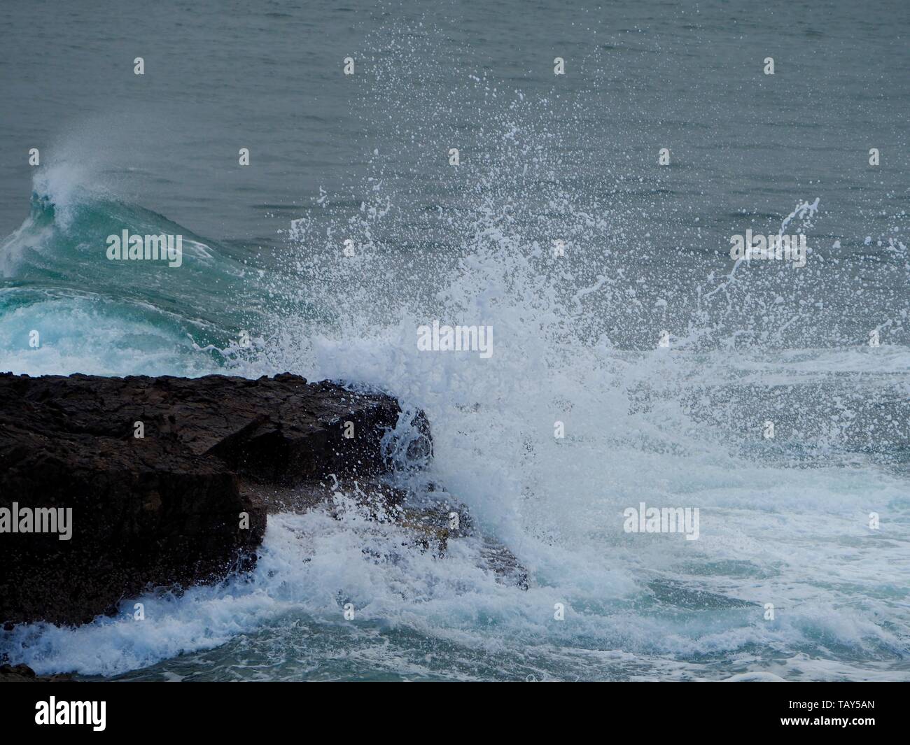 waves smashing into and crashing against rocks creating a splash ...