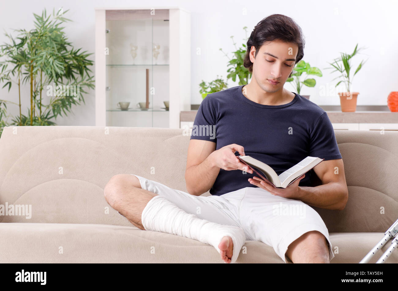 Leg injured young man suffering at home Stock Photo - Alamy